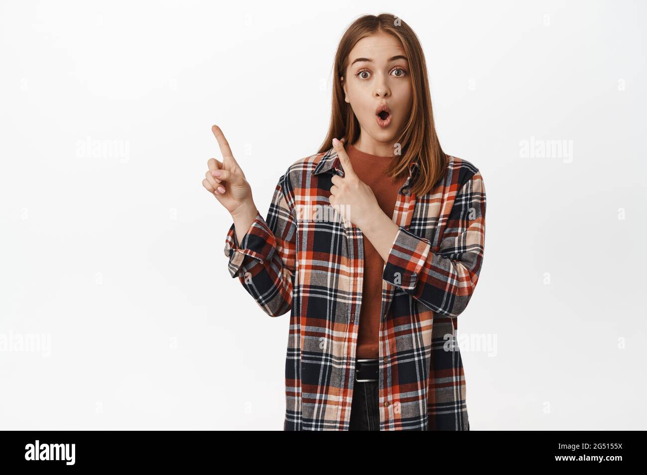 Surprised caucasian woman gasp in awe, pointing at upper left corner ...