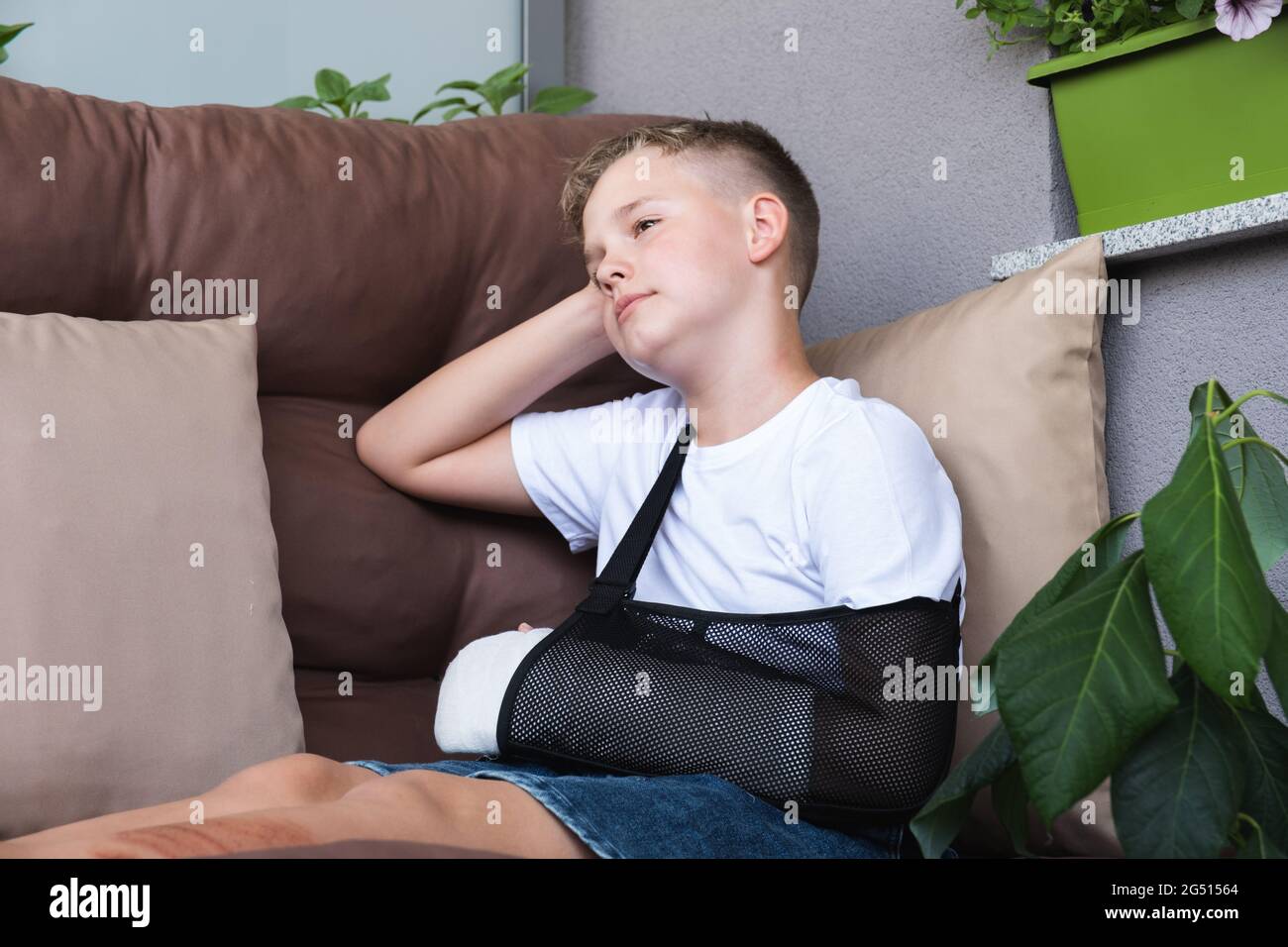 Sad child with a broken arm in home environment . Cast on hand of ...