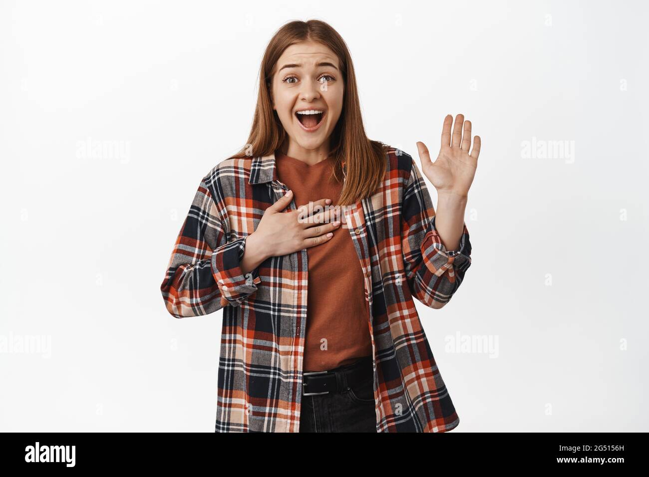 Excited young woman raising hand and place palm on heart, smiling happy ...