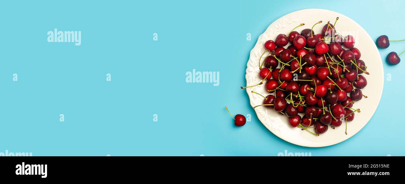 Cherry banner background. Red juicy sweet cherry on a white plate on a ...