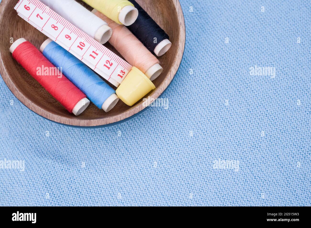 Top view of the colorful sewing threads with a thimble and a measuring ...