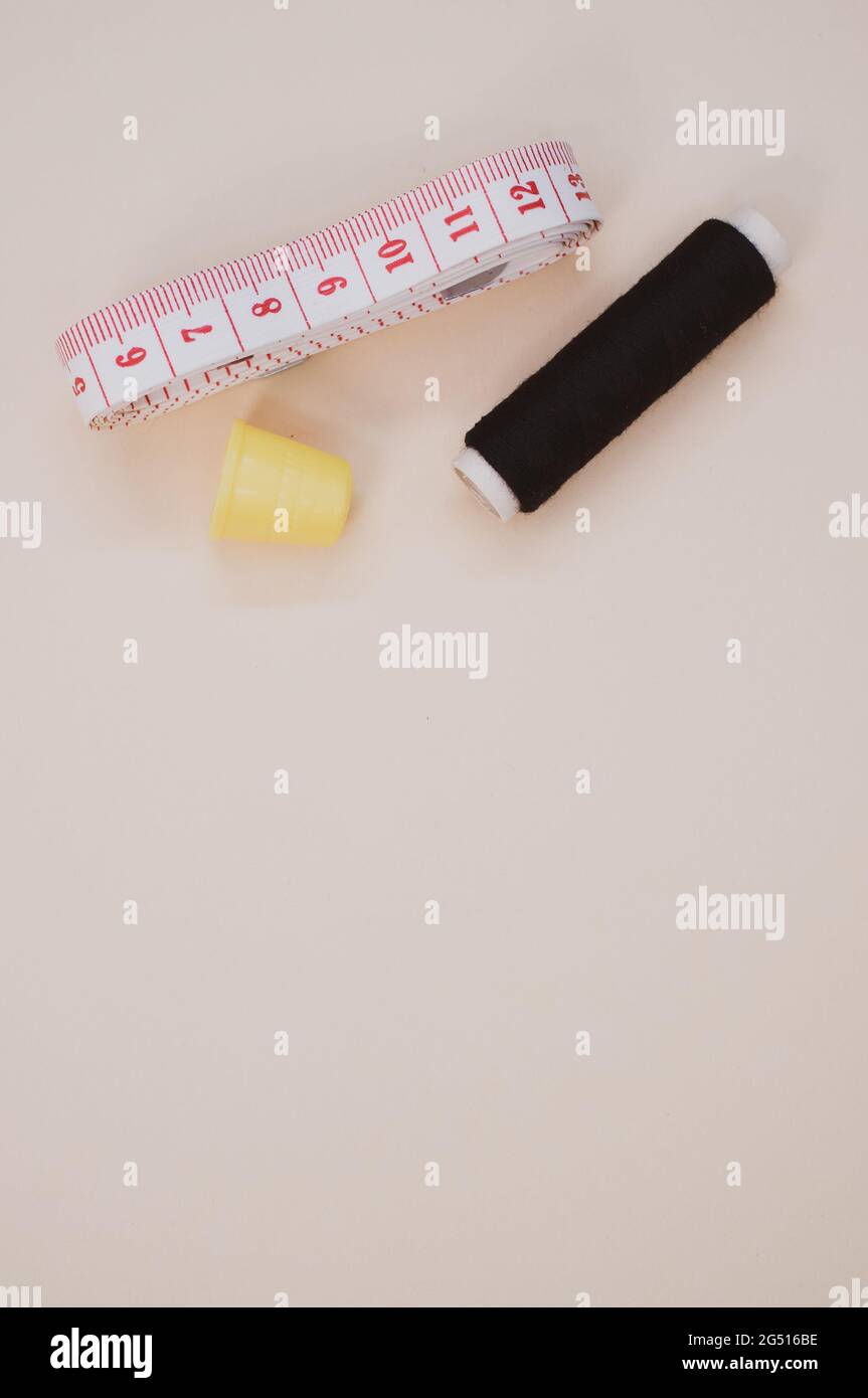 Top view of a black sewing thread with a thimble and a measuring tape ...