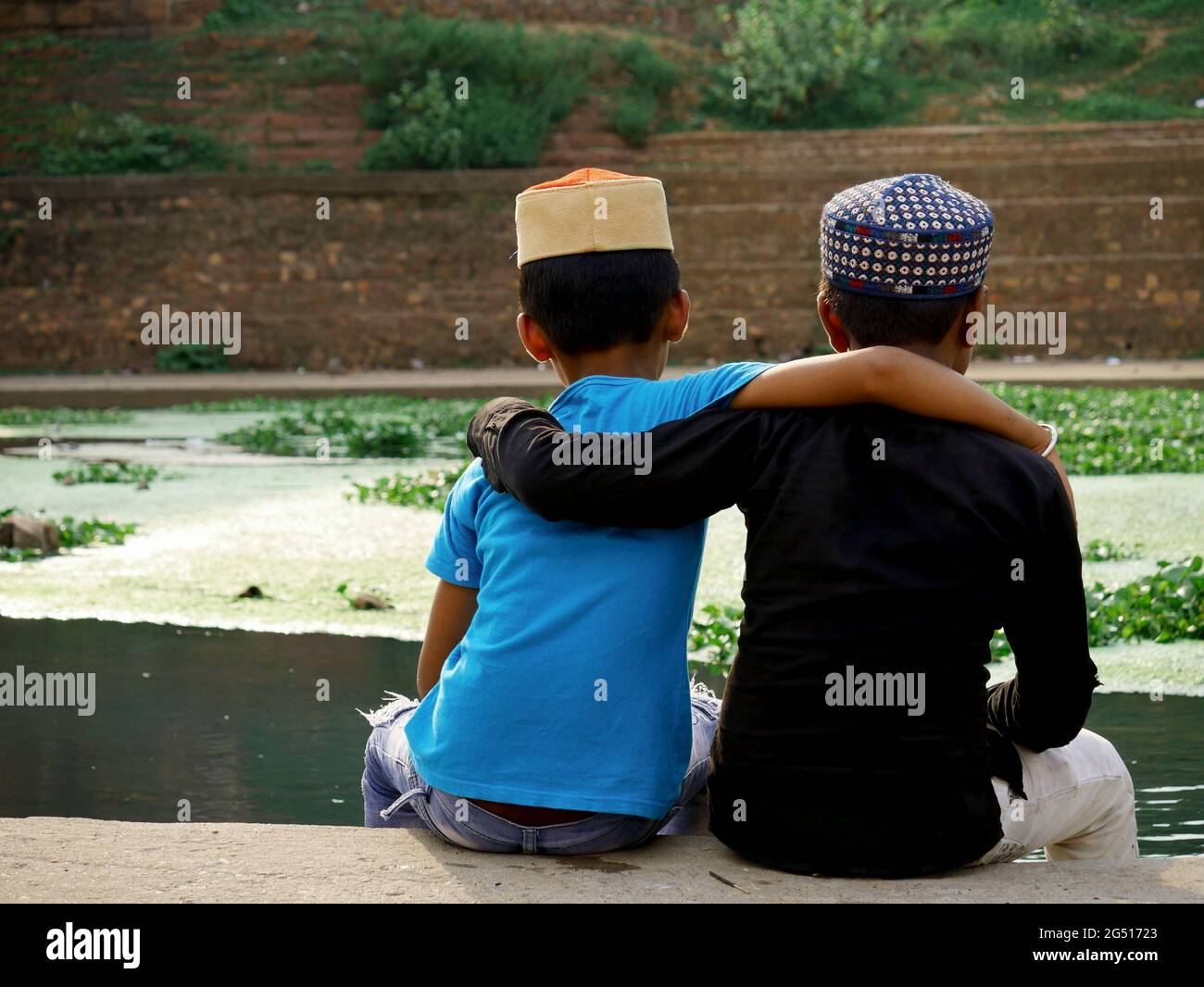 Two muslim kids friend sitting at river bank, lovely friendship concept ...