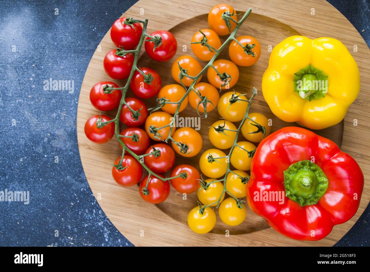 Top view of colorful bell peppers and cherry tomatoes on a wooden plate ...