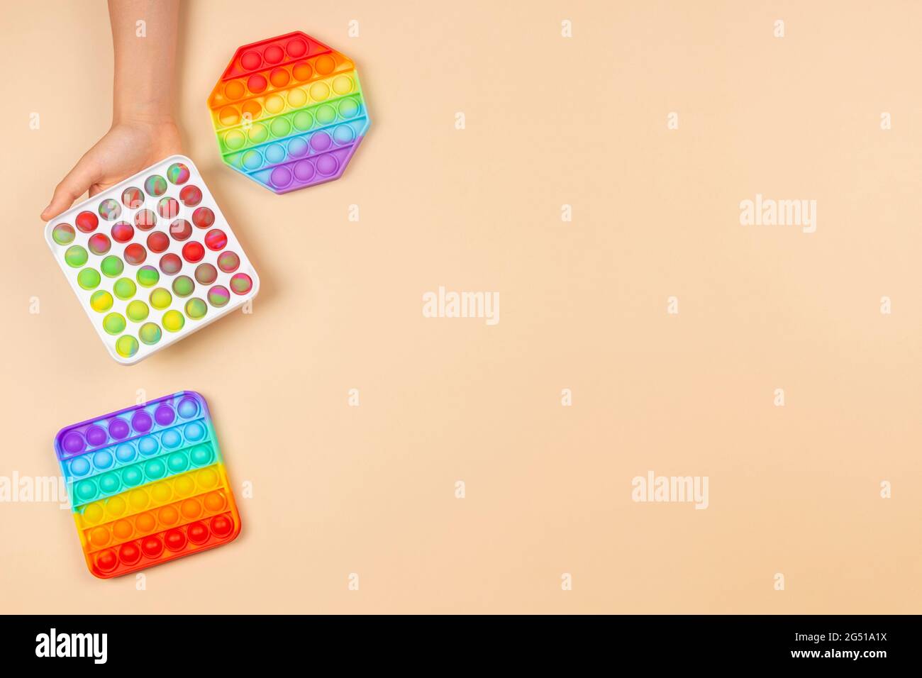 Kid hand holding pop it fidget toy on pastel background. Push pop-it ...