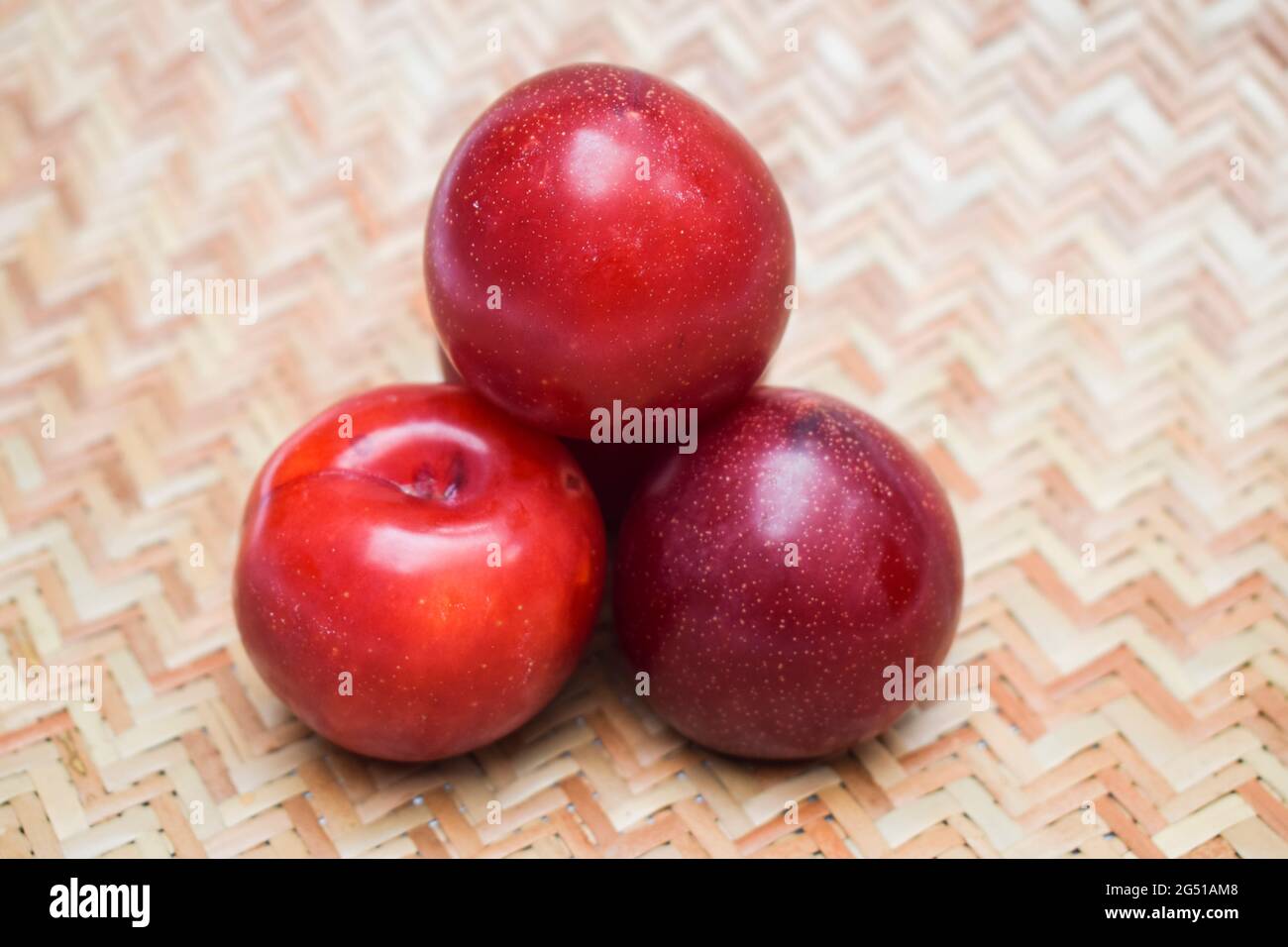 Plums fruits fresh organic bright red maroon color. On wicker bamboo ...