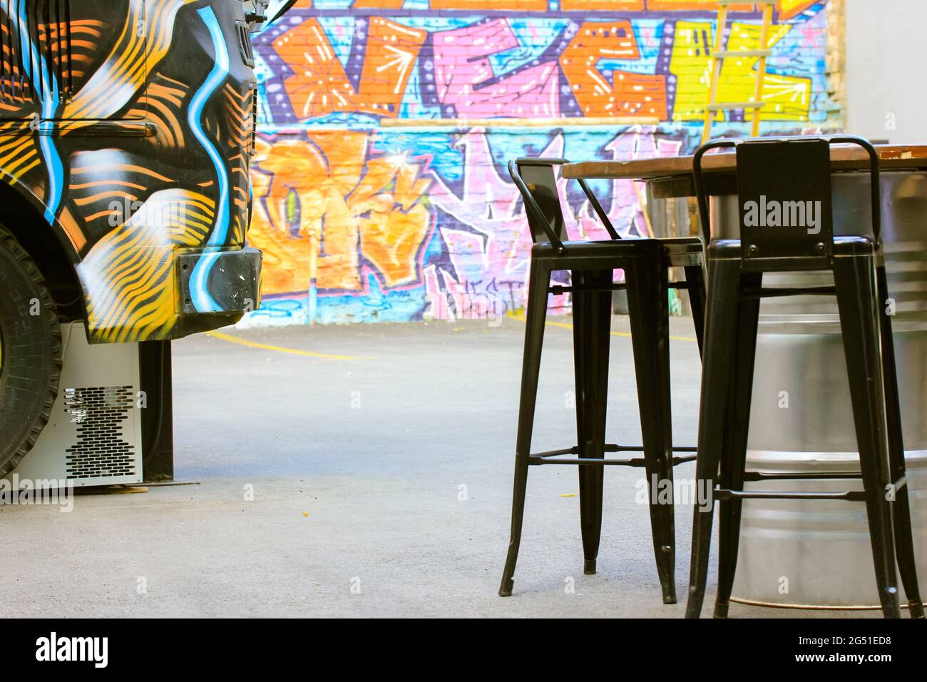 Black metal stylish bar stools, a metal barrel table against a colorful ...