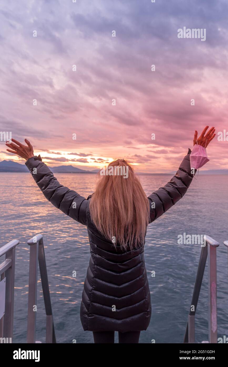 Faceless blonde woman in the coast raising her arms and holding her ...