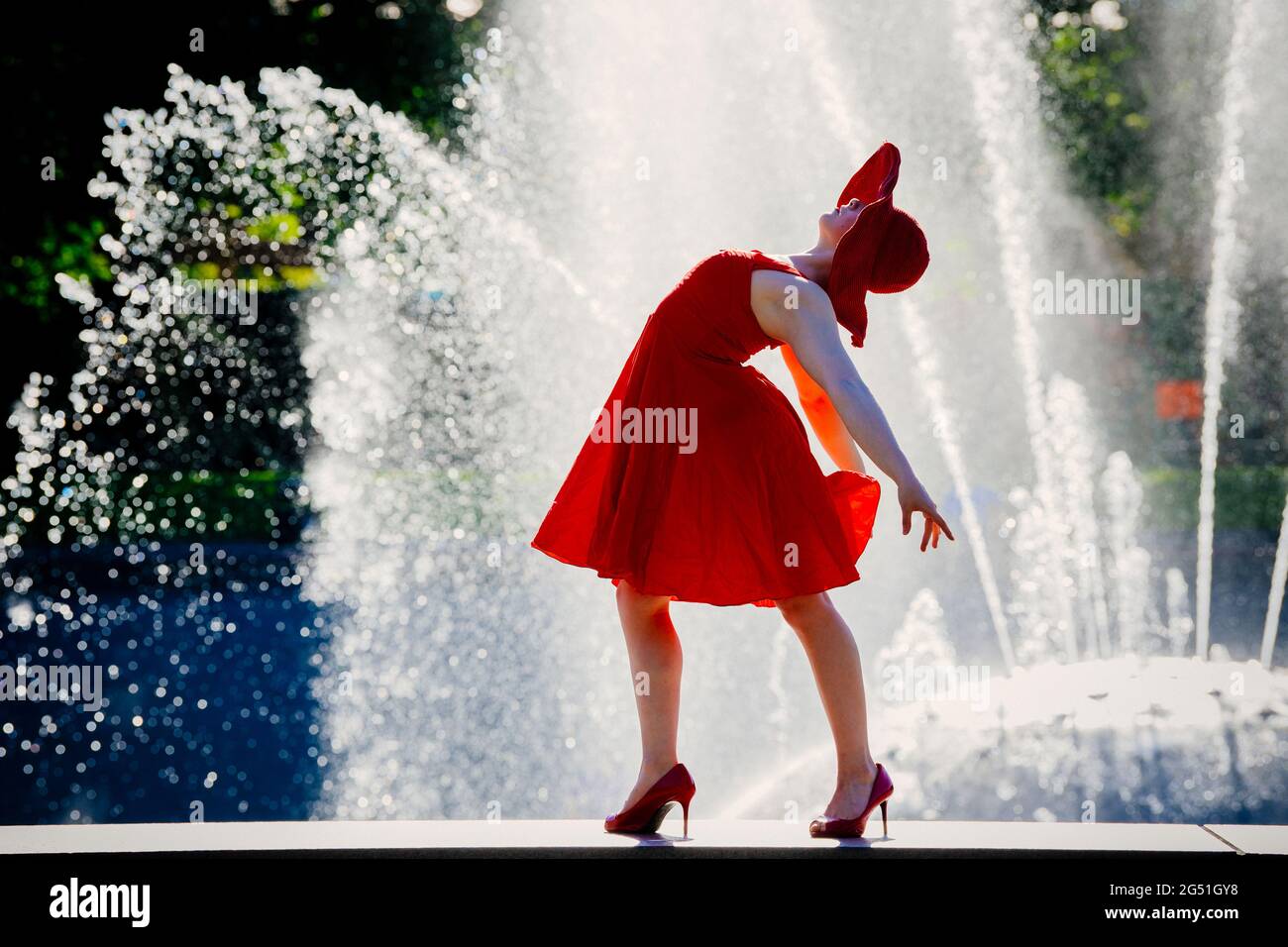 Woman in red dress dancing against fountain Stock Photo - Alamy