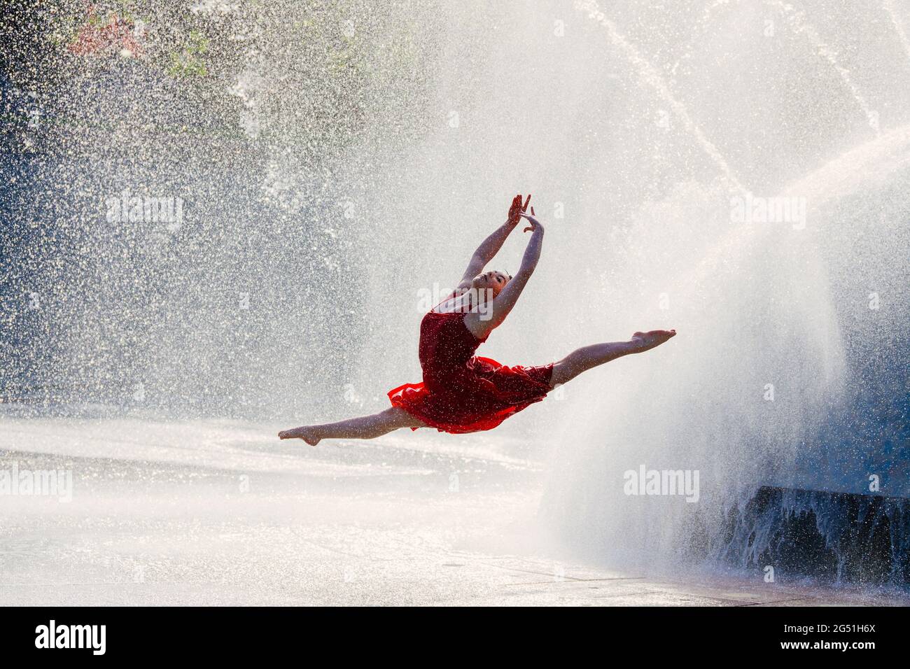 Woman in red dress dancing against fountain Stock Photo - Alamy
