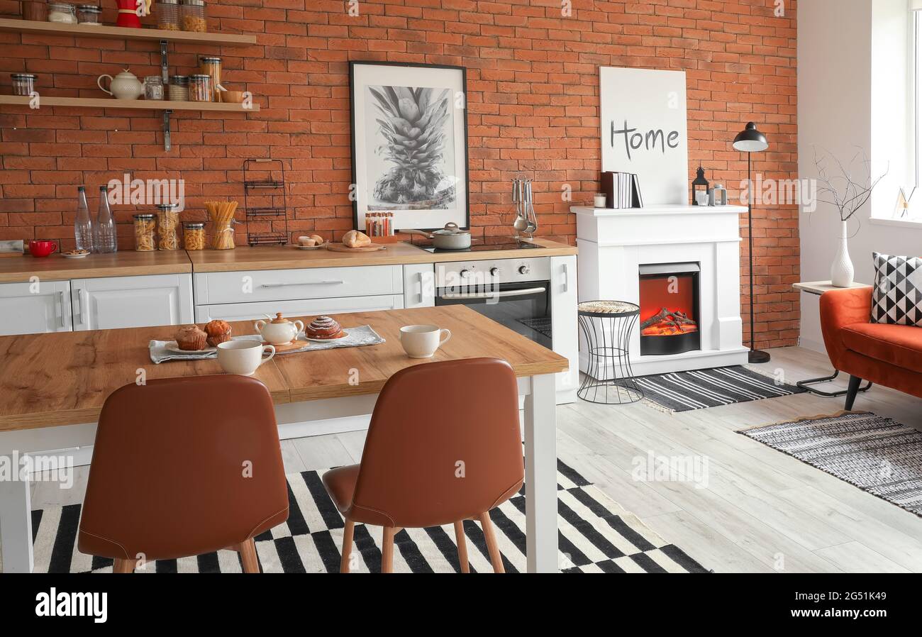 Stylish fireplace and dining table in interior of modern kitchen Stock ...