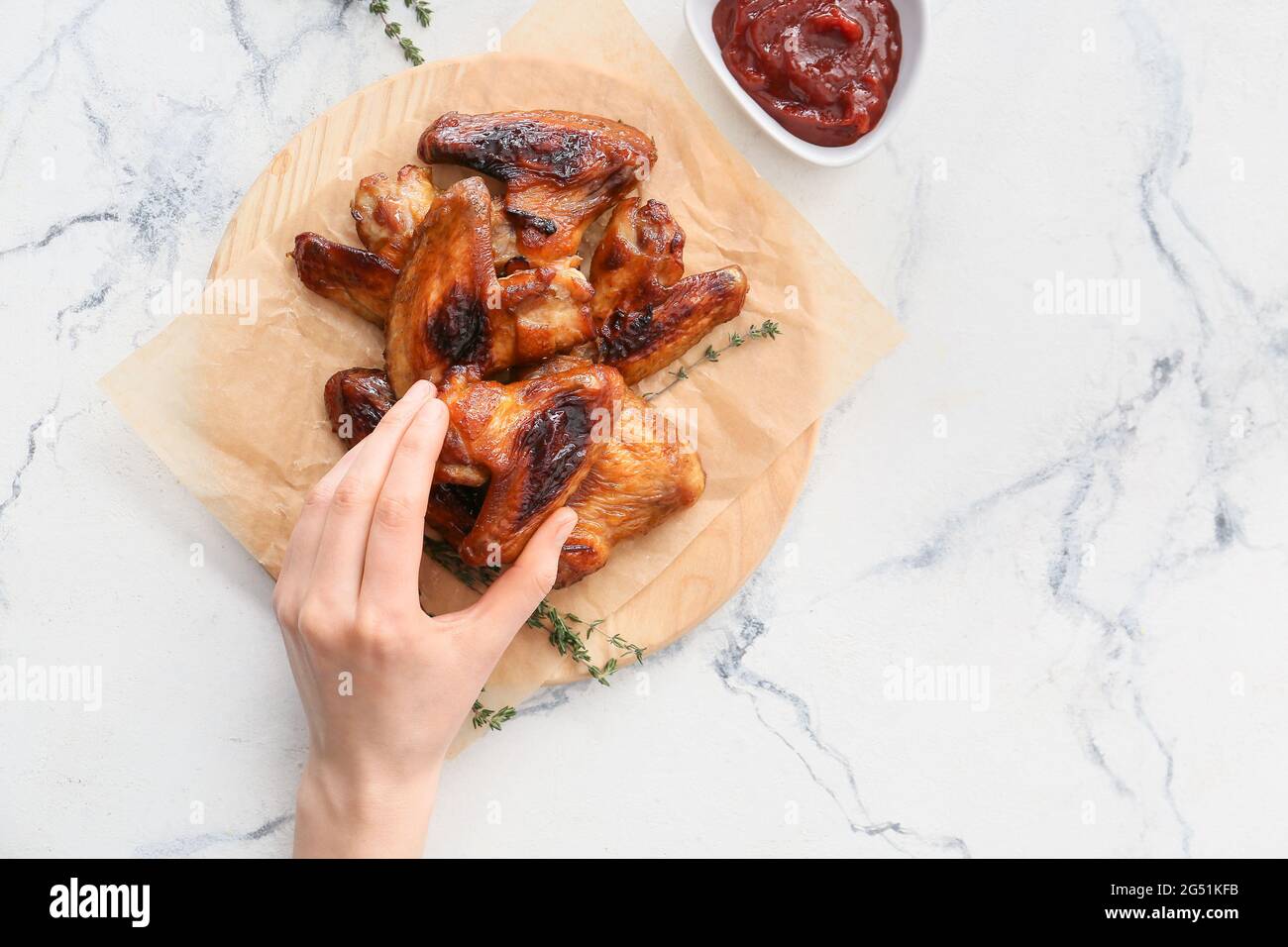 Woman eating roasted chicken wings on light background Stock Photo - Alamy