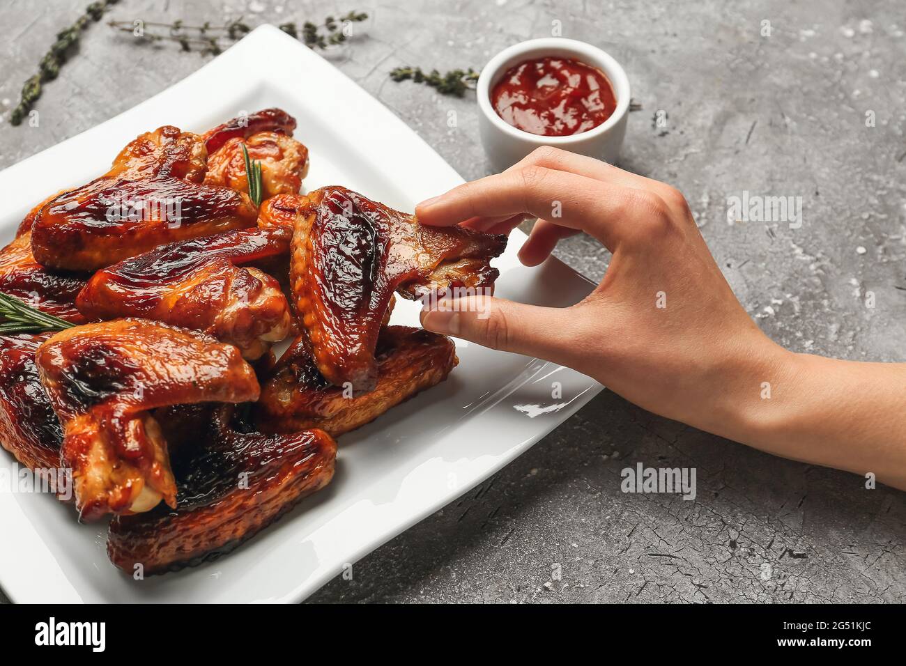 Woman eating roasted chicken wings on grey background Stock Photo - Alamy