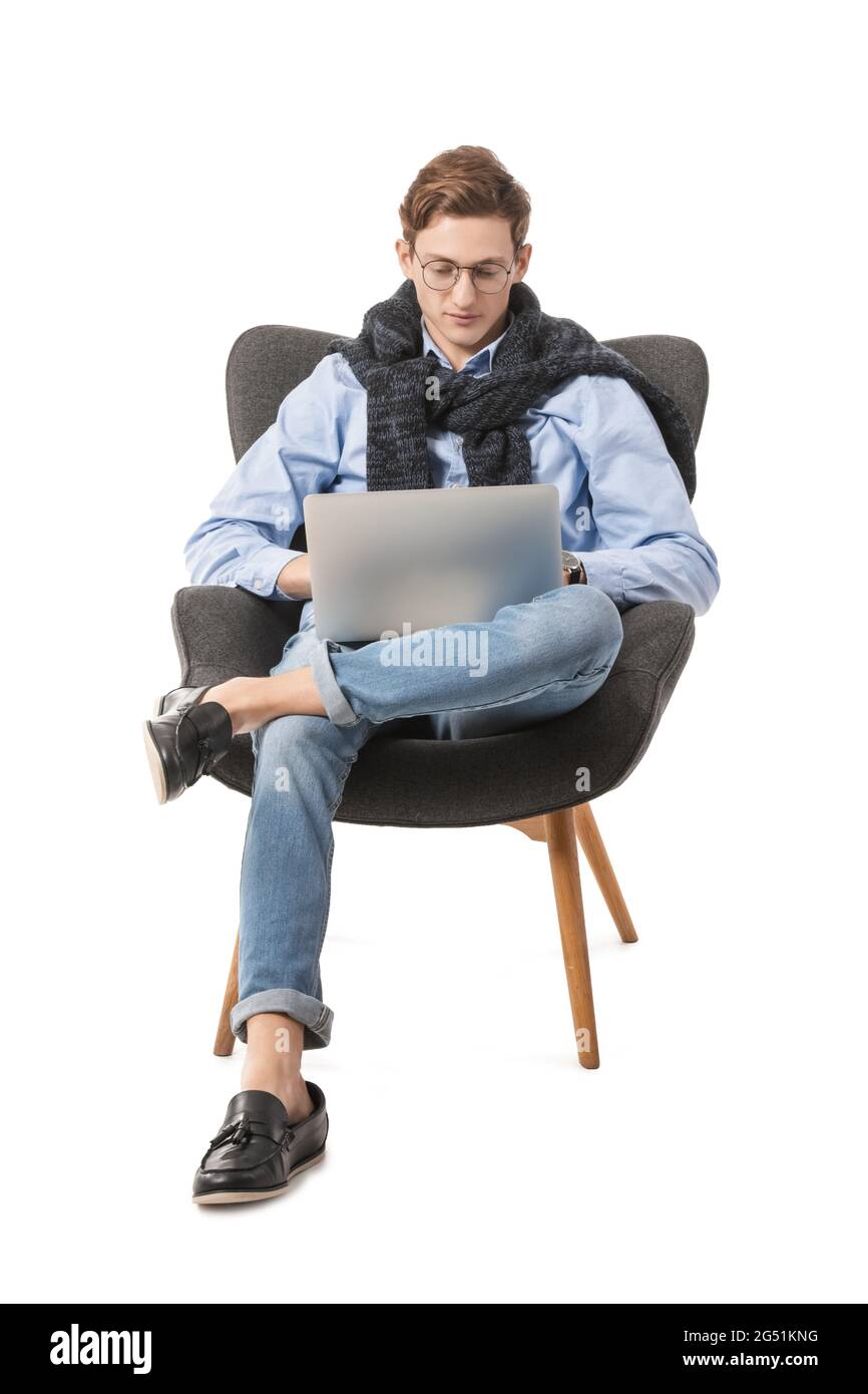 Young man with laptop sitting in armchair on white background Stock ...