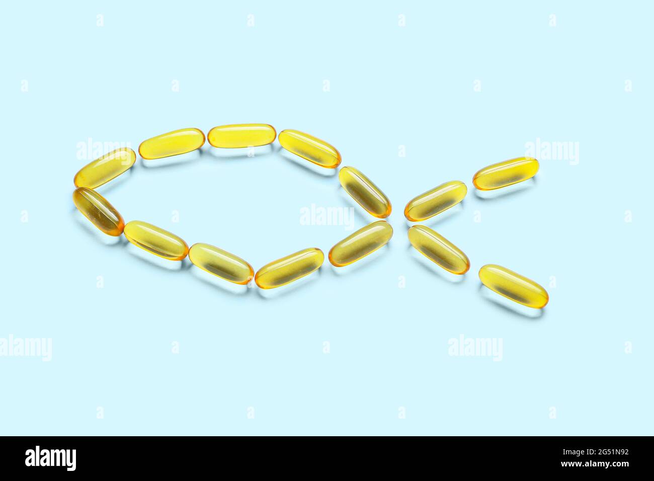 Fish made of oil capsules on color background Stock Photo - Alamy