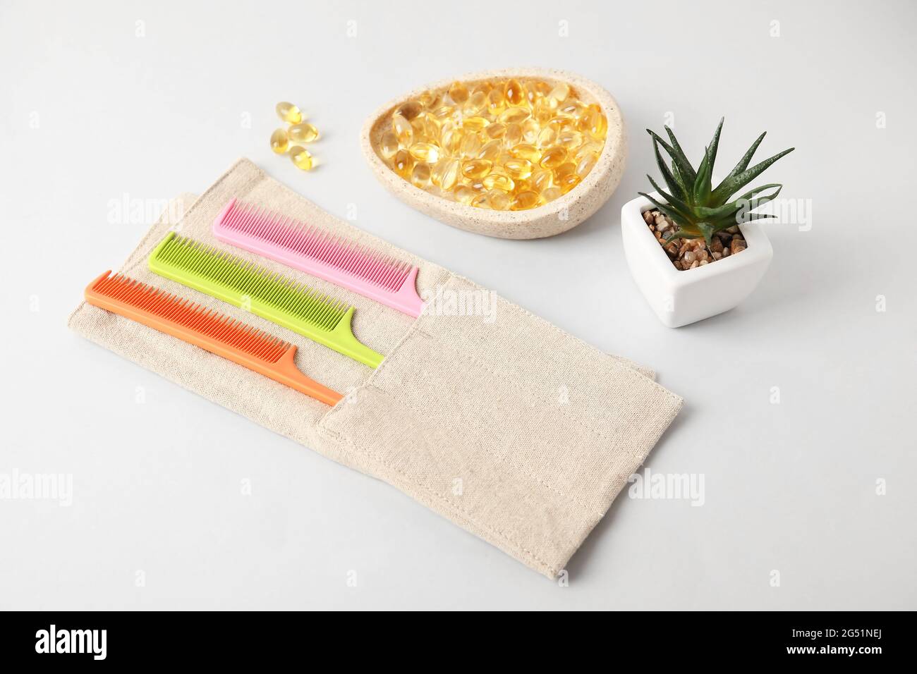 Hair combs, fish oil pills and houseplant on light background Stock ...