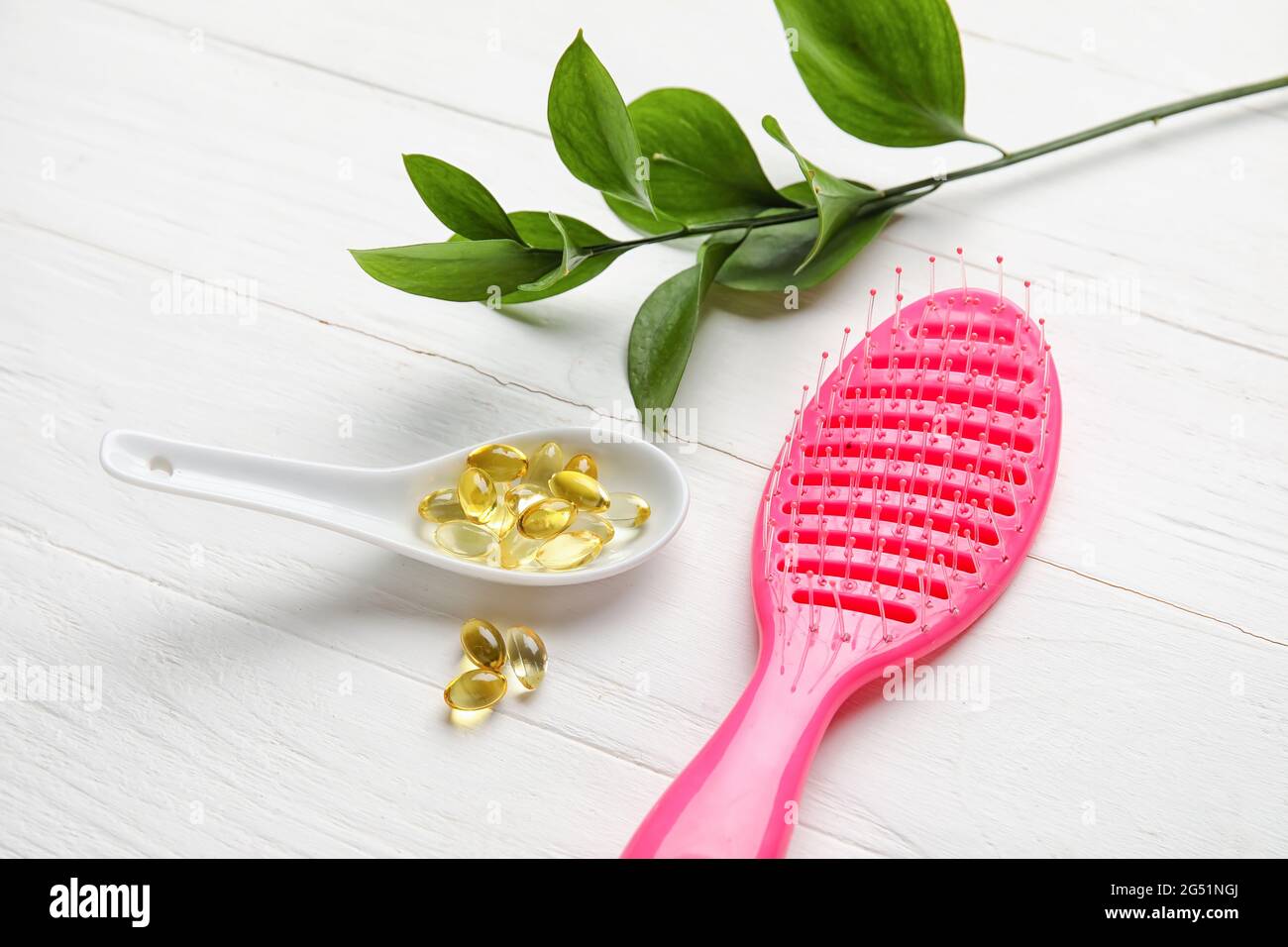 Hair brush and fish oil pills on light wooden background Stock Photo ...