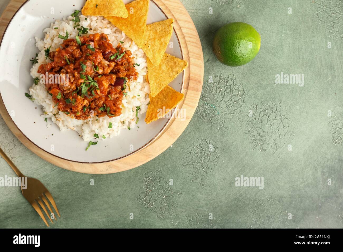 Plate with tasty chili con carne, rice, lime and nachos on color ...