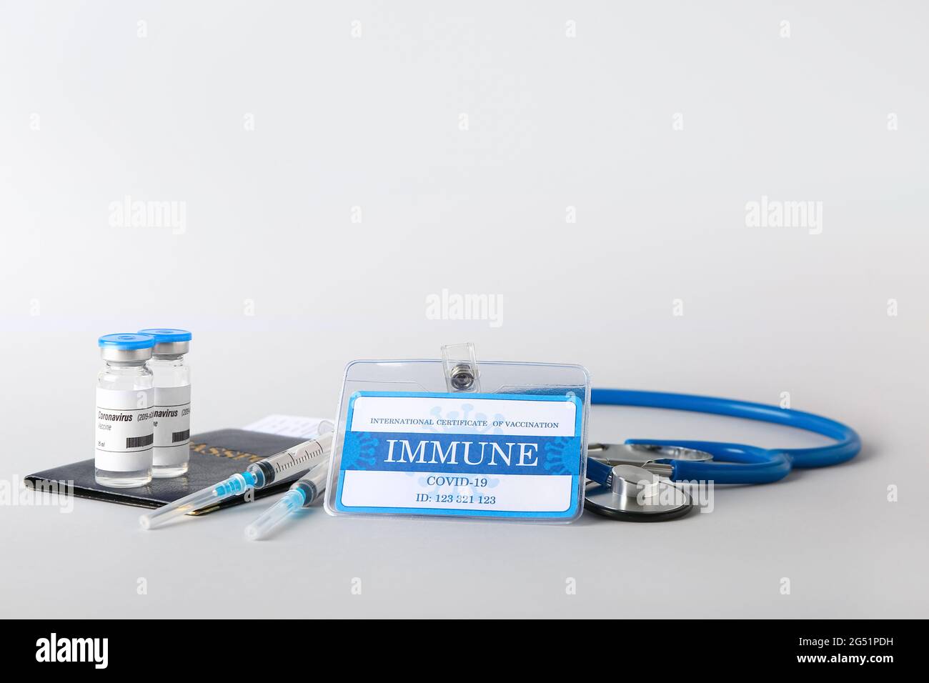 Immune card, passport, stethoscope and covid-19 vaccine on grey ...