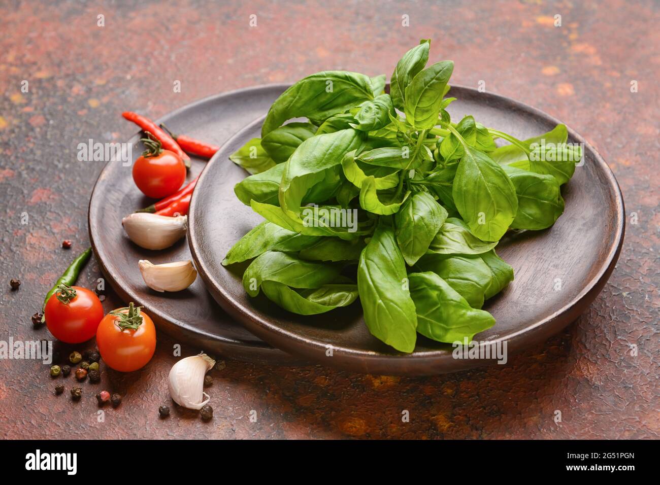 Plates with fresh basil leaves, spices and tomatoes on grunge ...