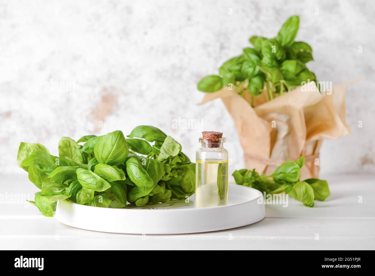 Composition with fresh basil and bottle of essential oil on light ...