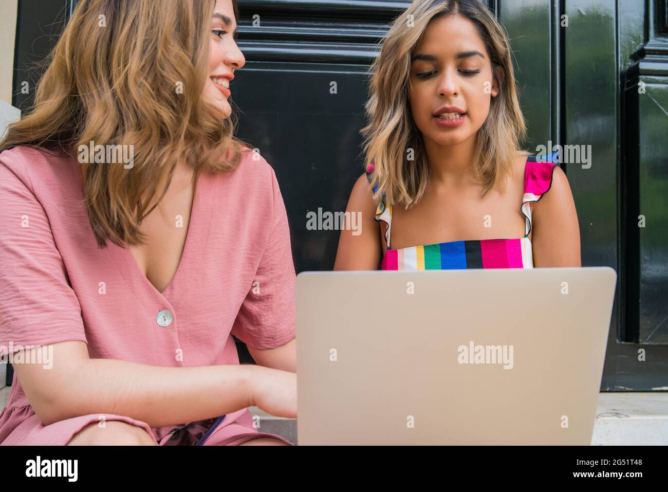 Two friends using laptop outdoors Stock Photo - Alamy