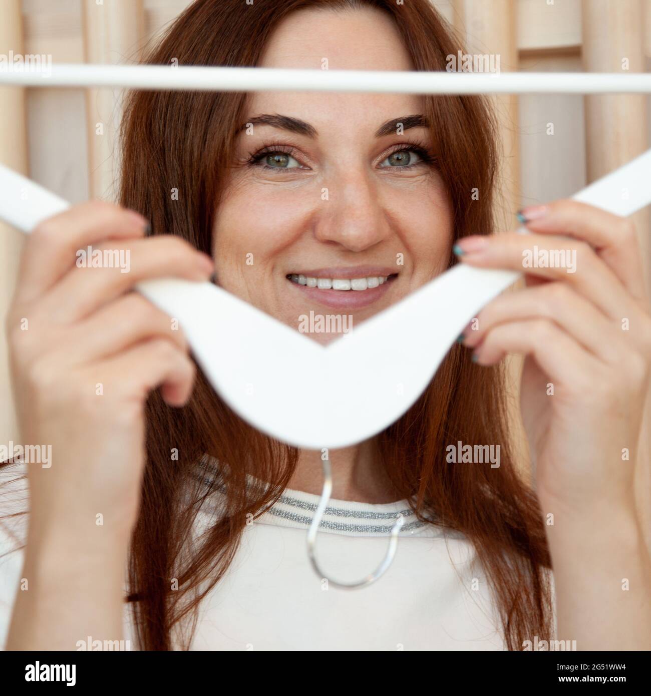 Beautiful young woman hanging empty white hanger on white stylish ...