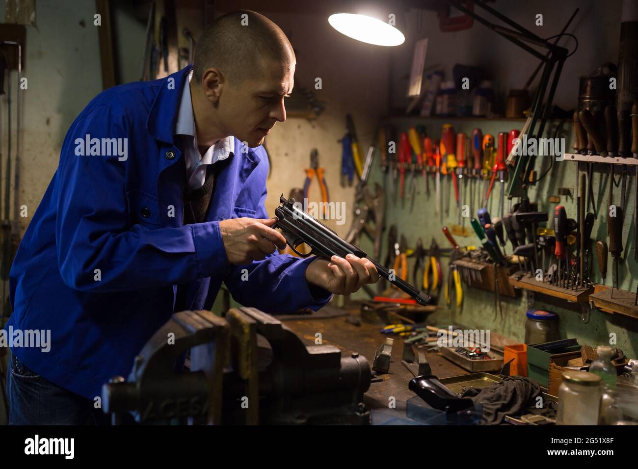 Skilled craftsman of weapons workshop repairing of small-bore handgun ...