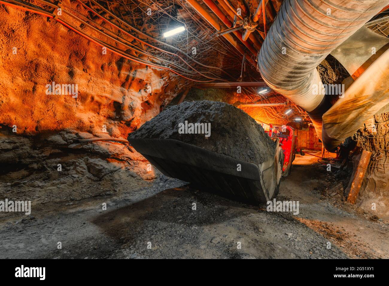 An underground loading machine carries a full bucket of ore. Special ...