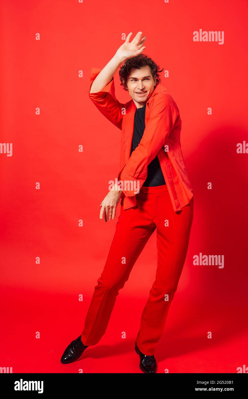 Portrait of a tall handsome man dressed in red shirt posing on the red ...