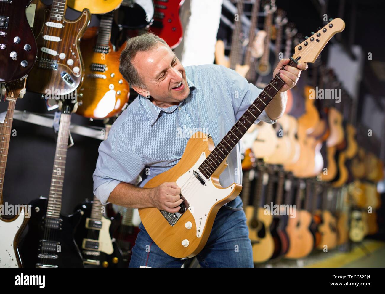 Adult guitarist is playing on electric guitar in music store Stock ...