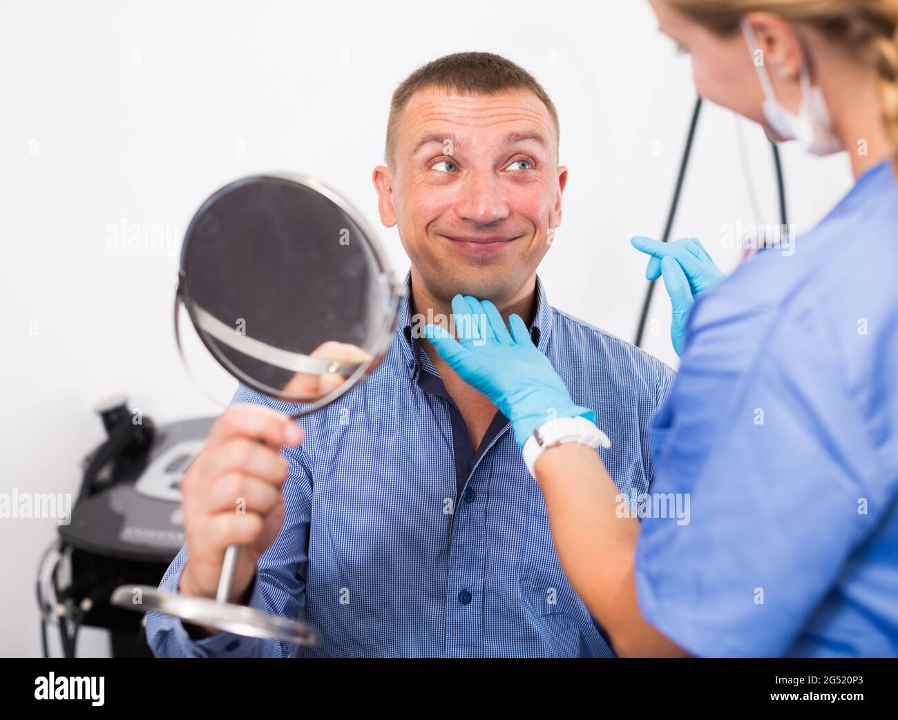 Woman doctor is examining patient behind mirror before the procedure ...