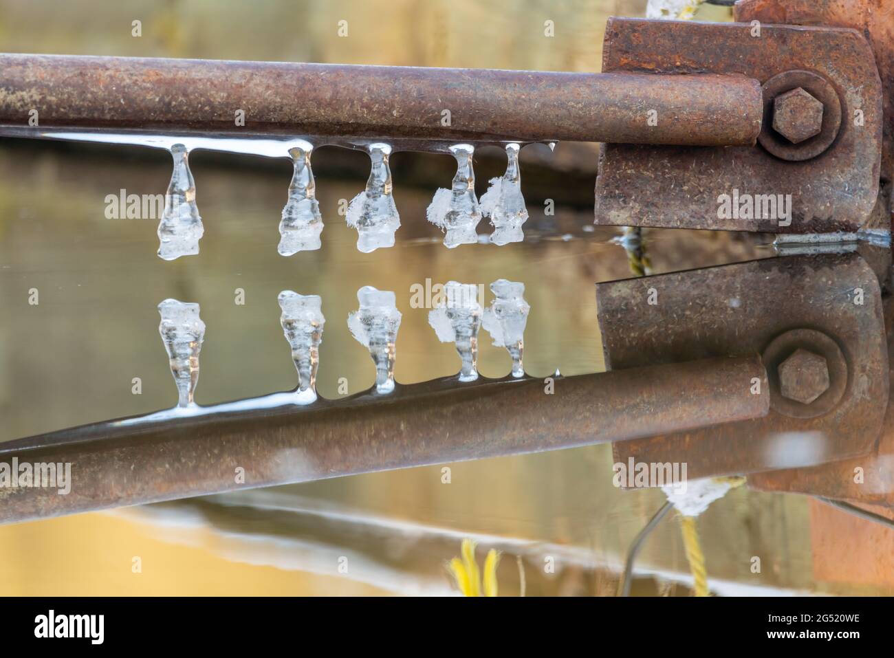 Icicles frozen ice hanging off rusting pole above water with stunning ...