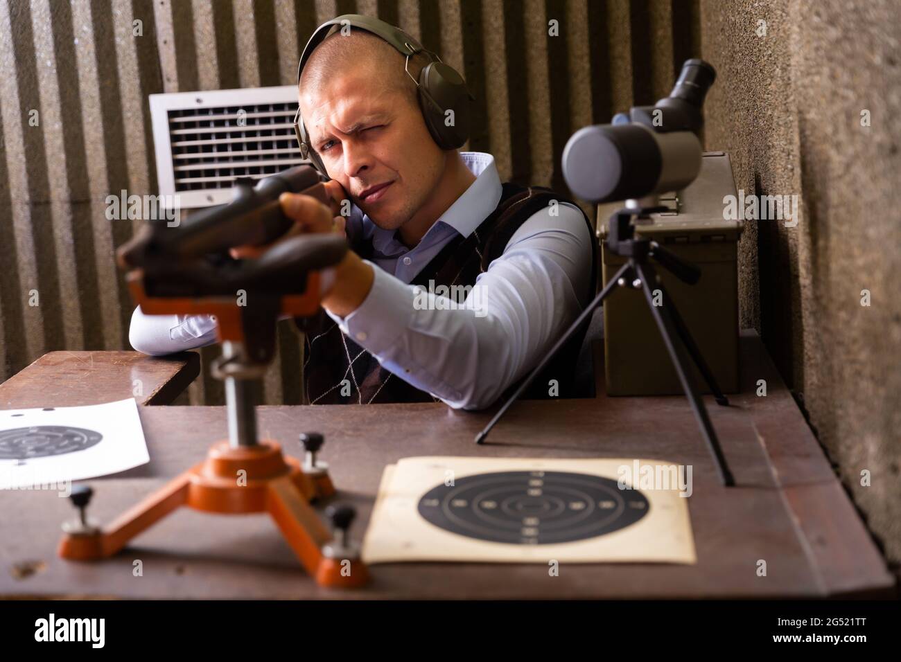 Man aims at a target with a semi-automatic rifle in shooting range ...
