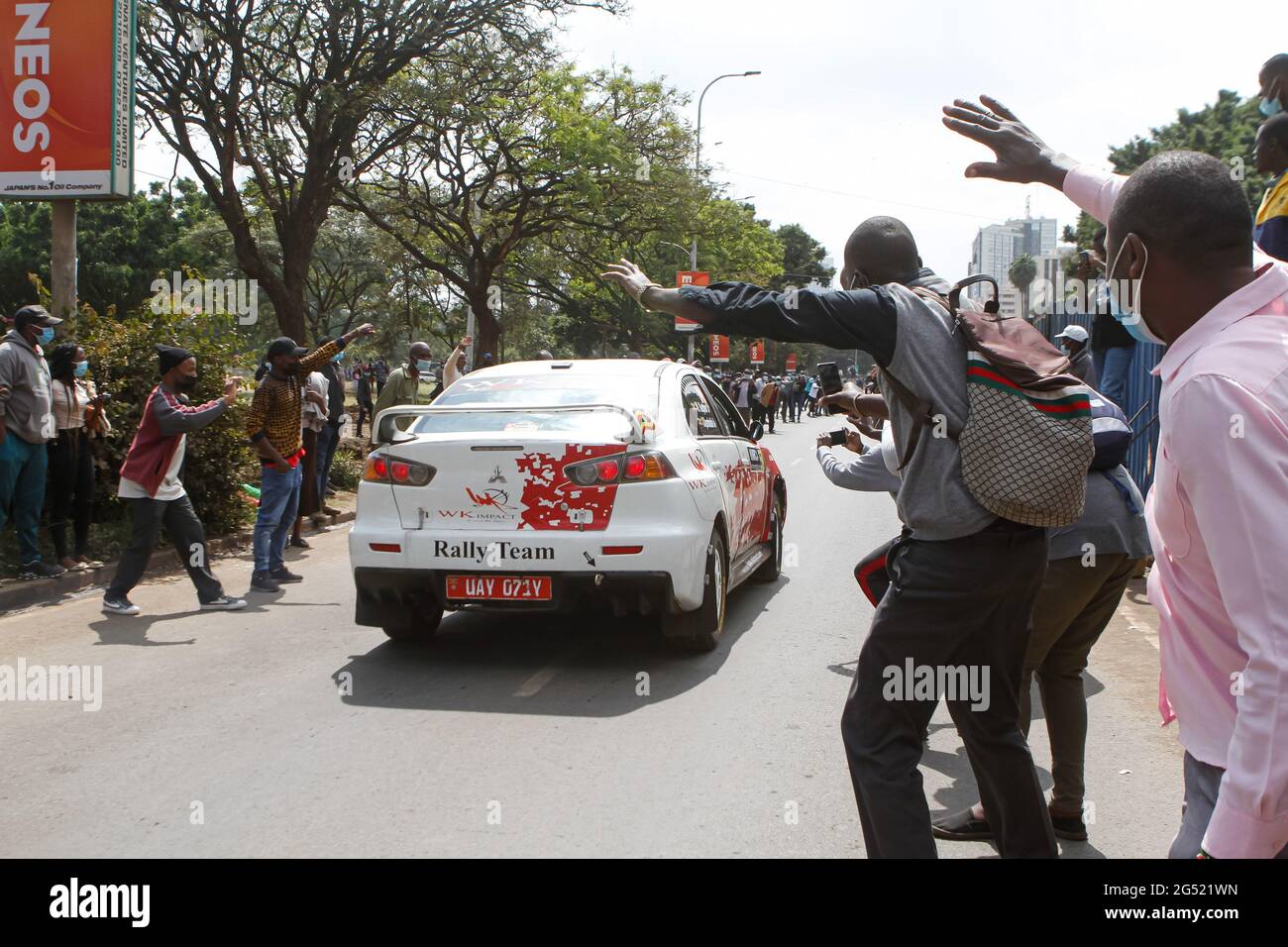 Kenyan spectators wave to one of the safari rally racing cars along ...