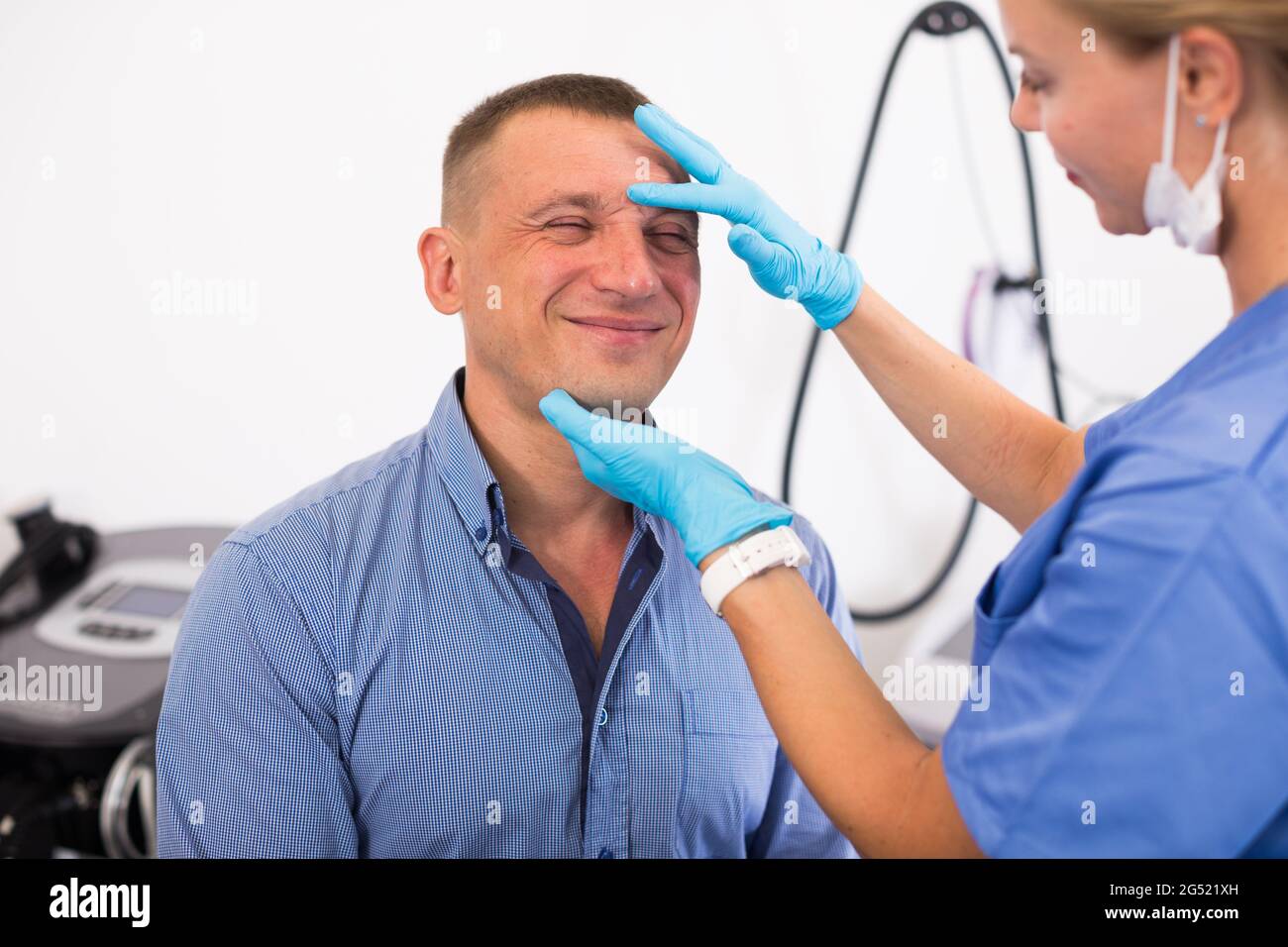 Female doctor is examining face of client after procedure Stock Photo ...
