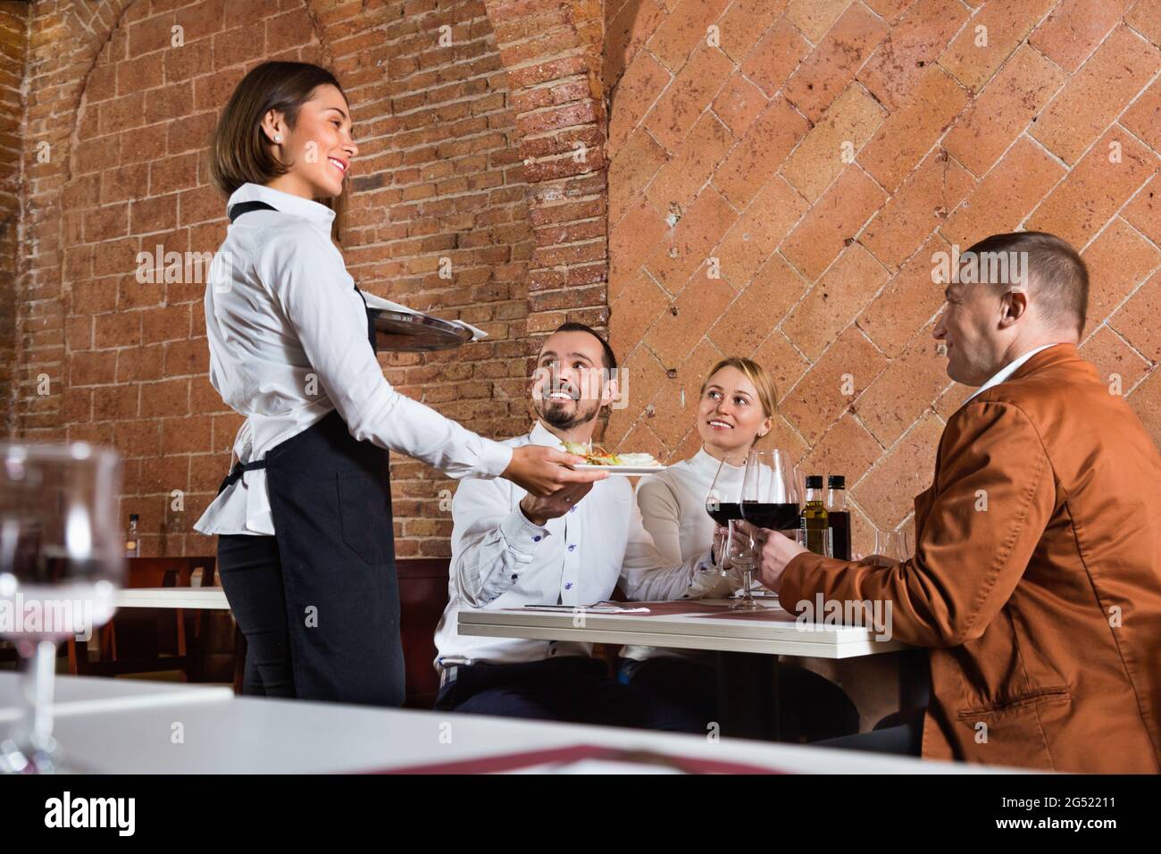 Female waiter bringing order to visitors Stock Photo - Alamy