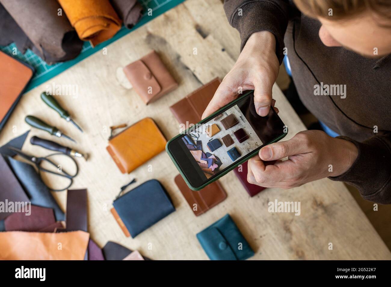 Top view male tanner hands taking photo of exclusive leatherwork ...