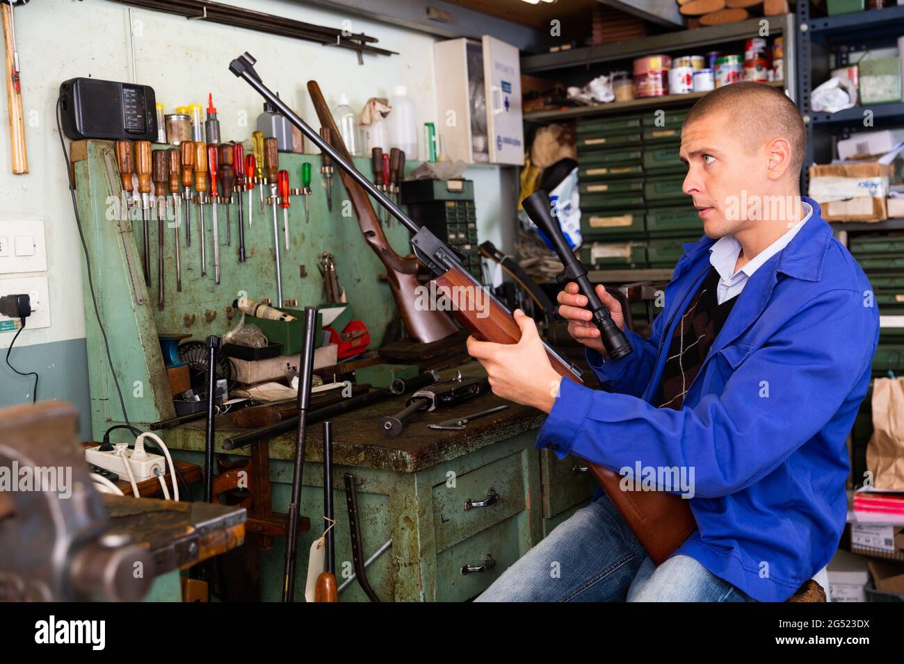 Gunsmith attaches a telescopic sight to rifle in weapons workshop Stock ...