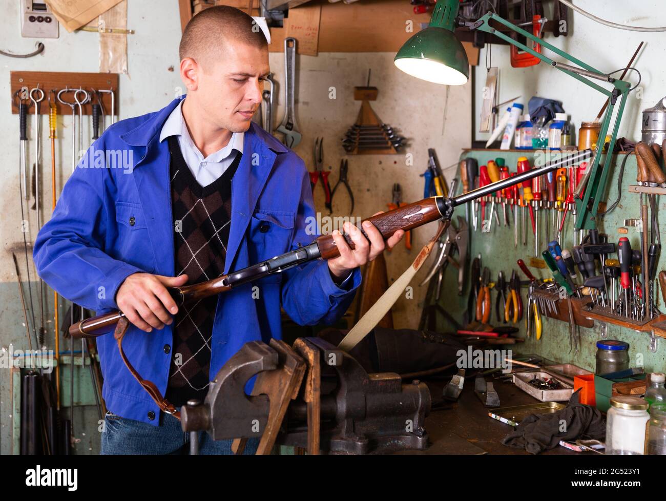 Gunsmith performing checkout of single-barrelled shotgun in weapons ...