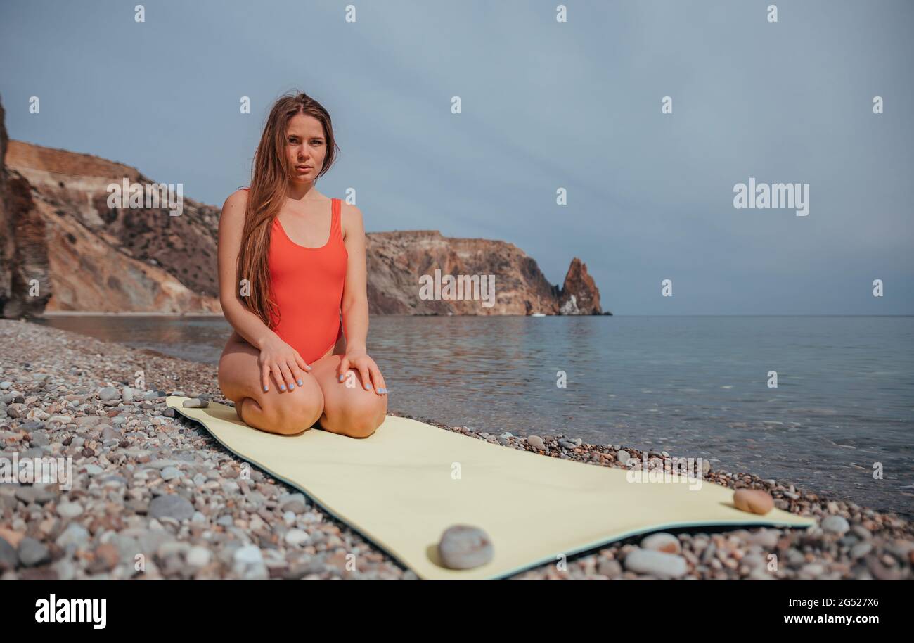 Young woman in red swimsuit with long hair practicing stretching Stock ...