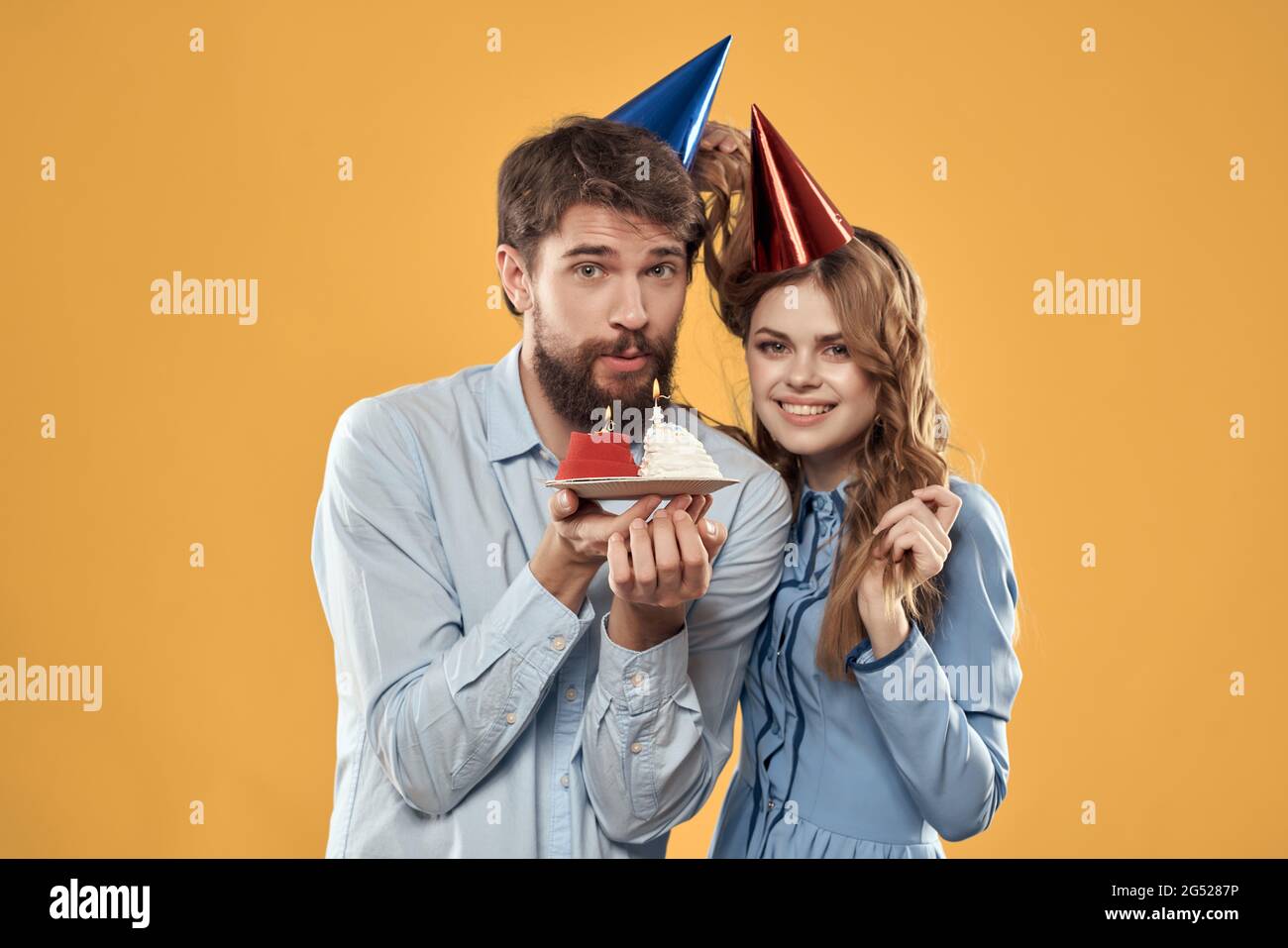 young couple birthday party fun caps on the head yellow background ...