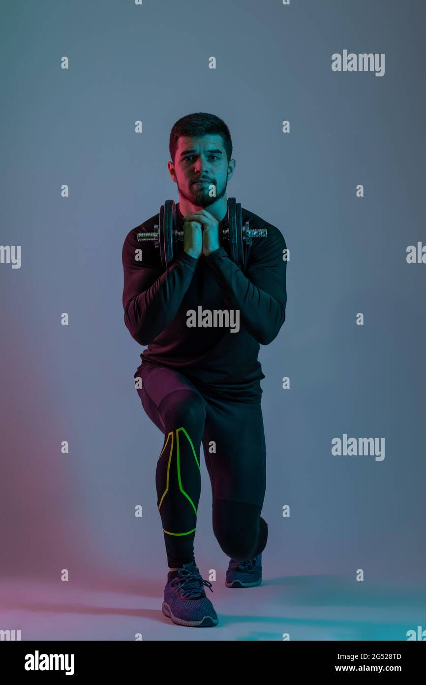 Sporty young man doing forward lunges with dumbbell Stock Photo - Alamy