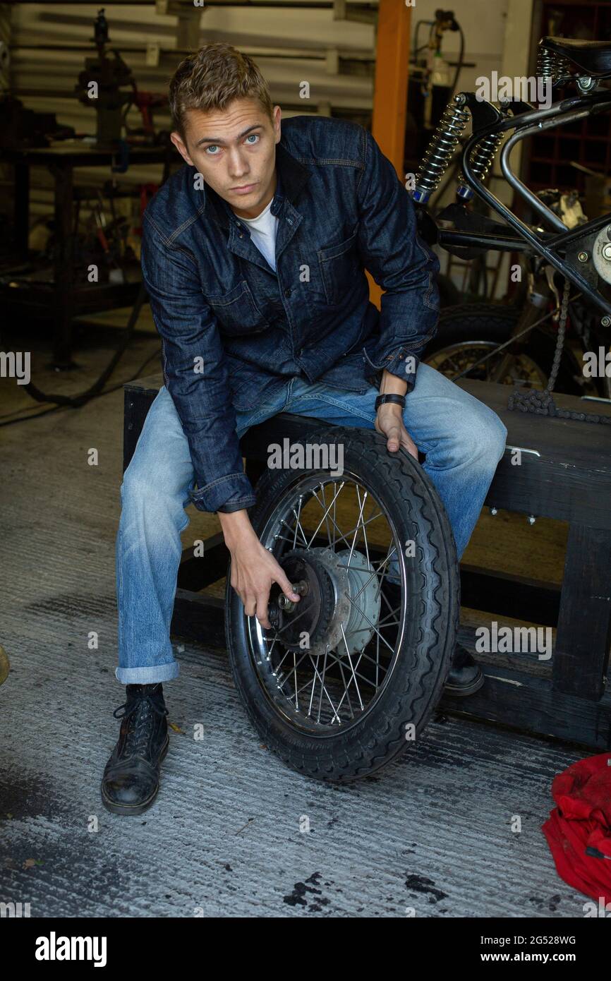 Young Man repairing a motorcycle wheel in a garage workshop Stock Photo ...