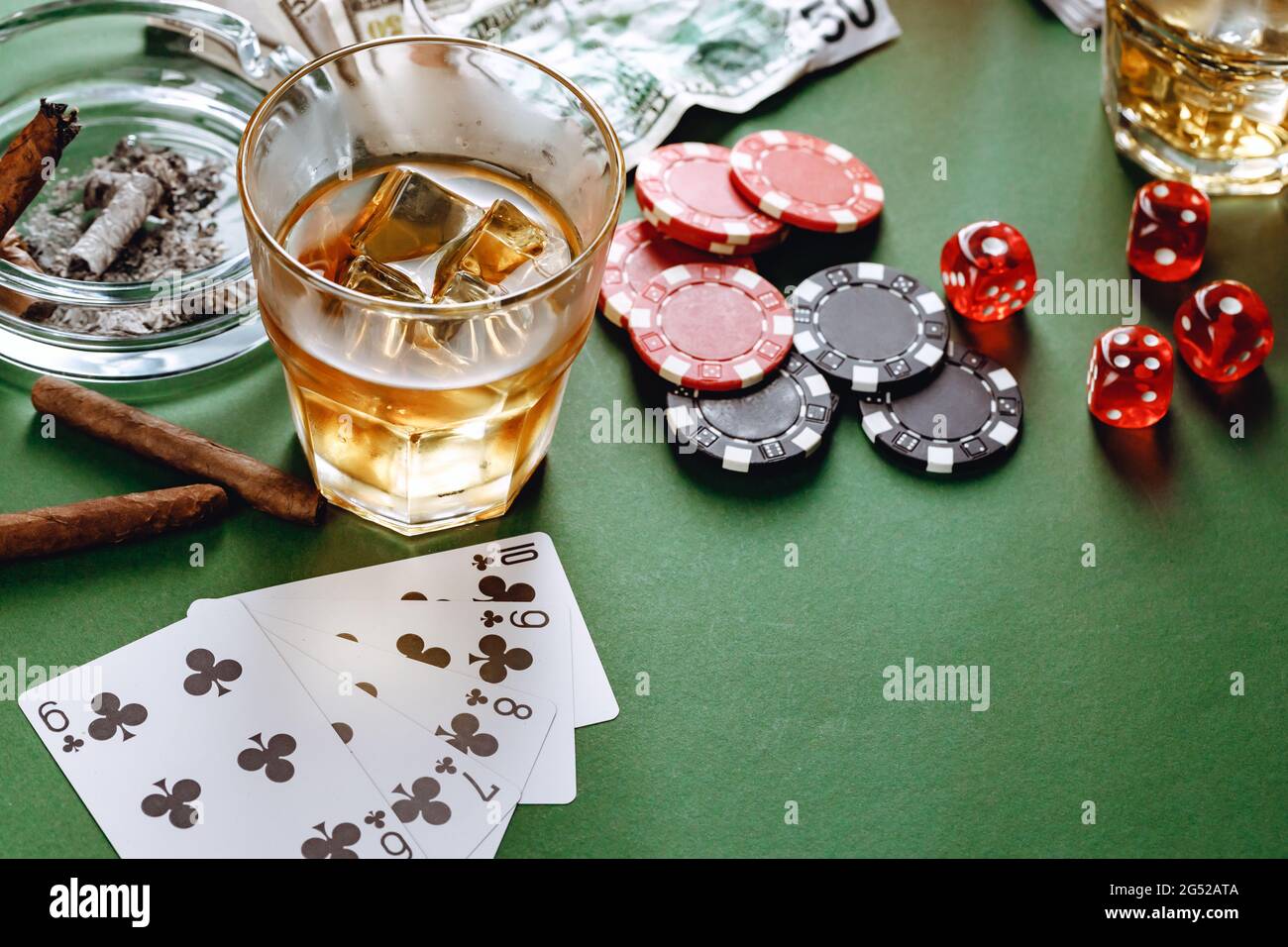 Glass of whiskey, cigar, playing cards and chips on green background ...
