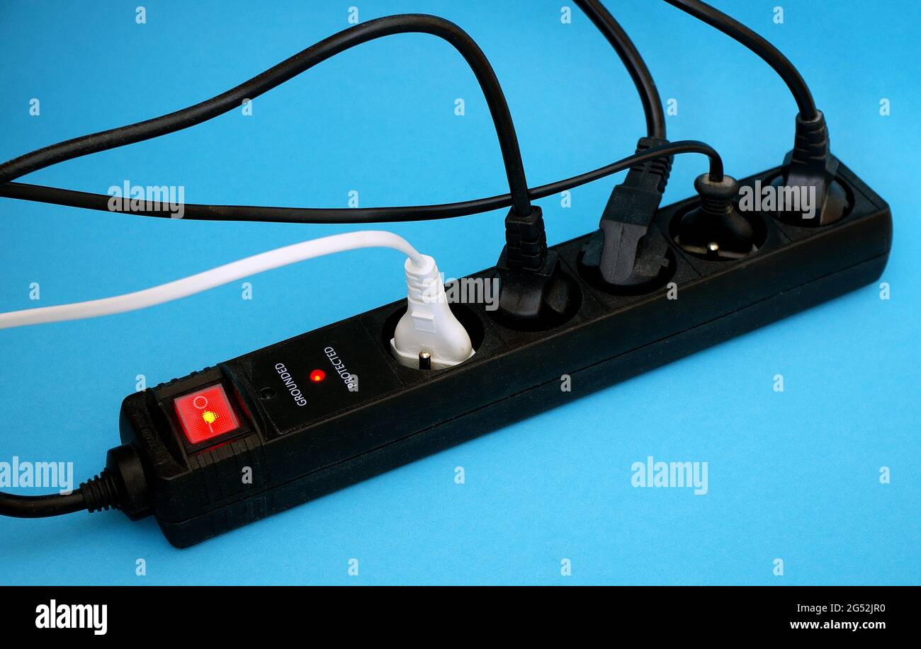 Black power surge protector with cables and light on blue background ...
