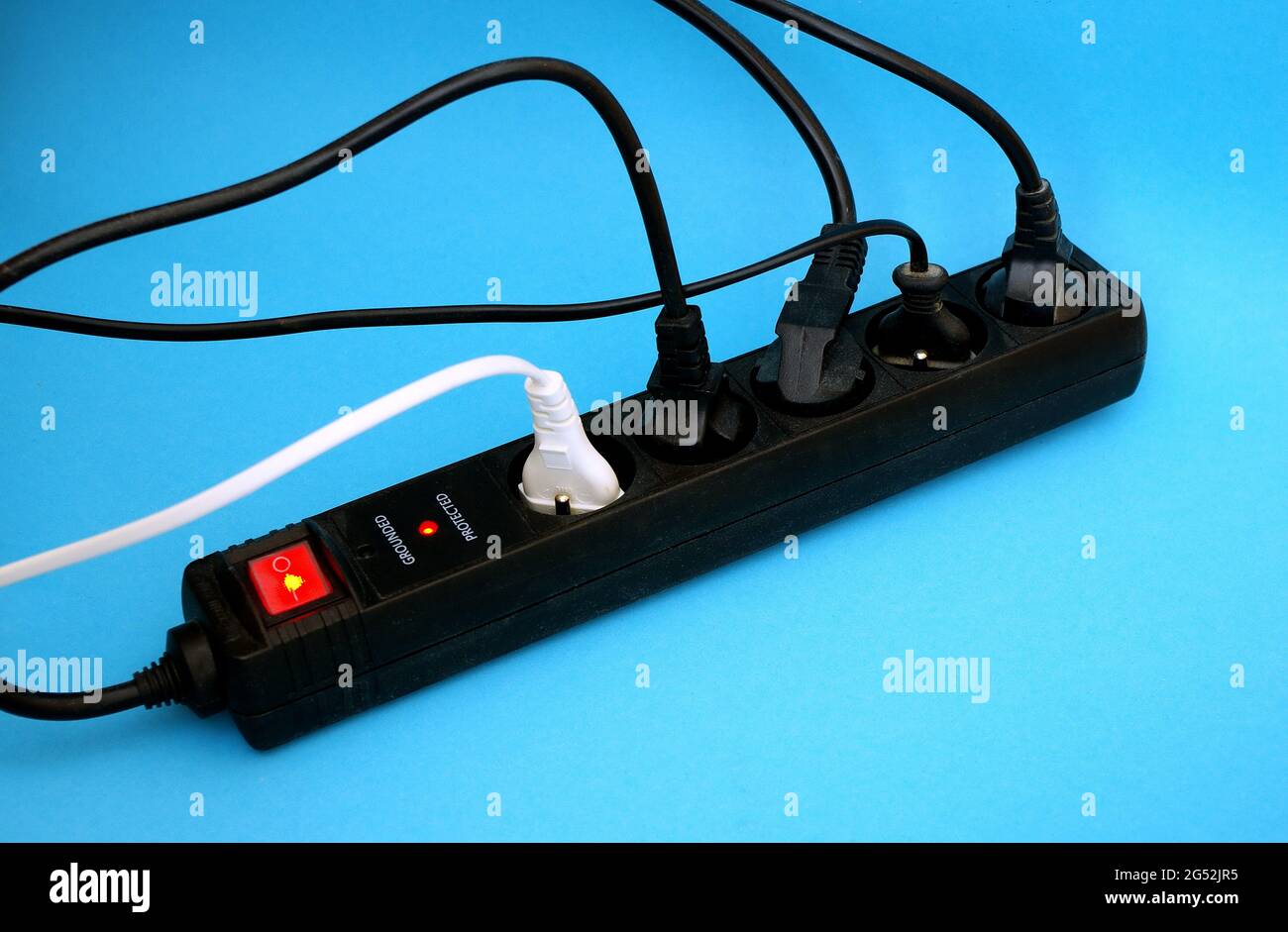 Black power surge protector with cables and light on blue background ...