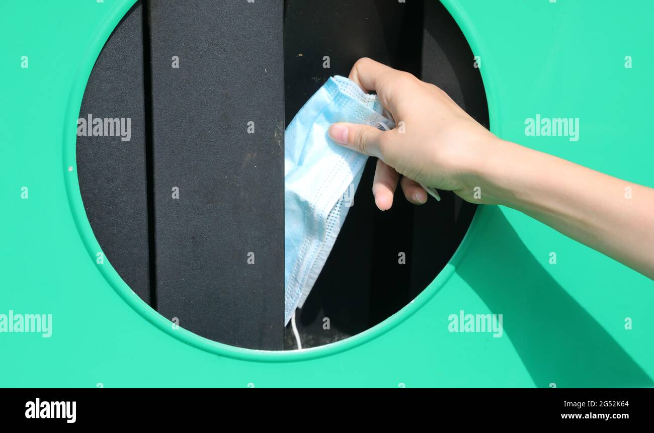 hand of a guy who throws surgical mask used in the trash for recycling ...