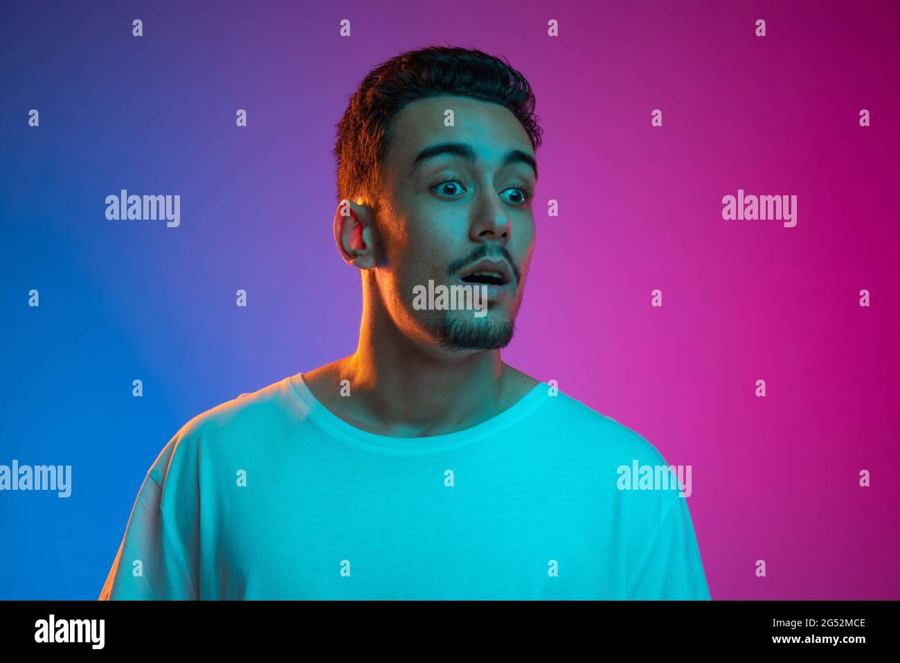 Portrait of Latina young man posing isolated on gradient purple pink ...