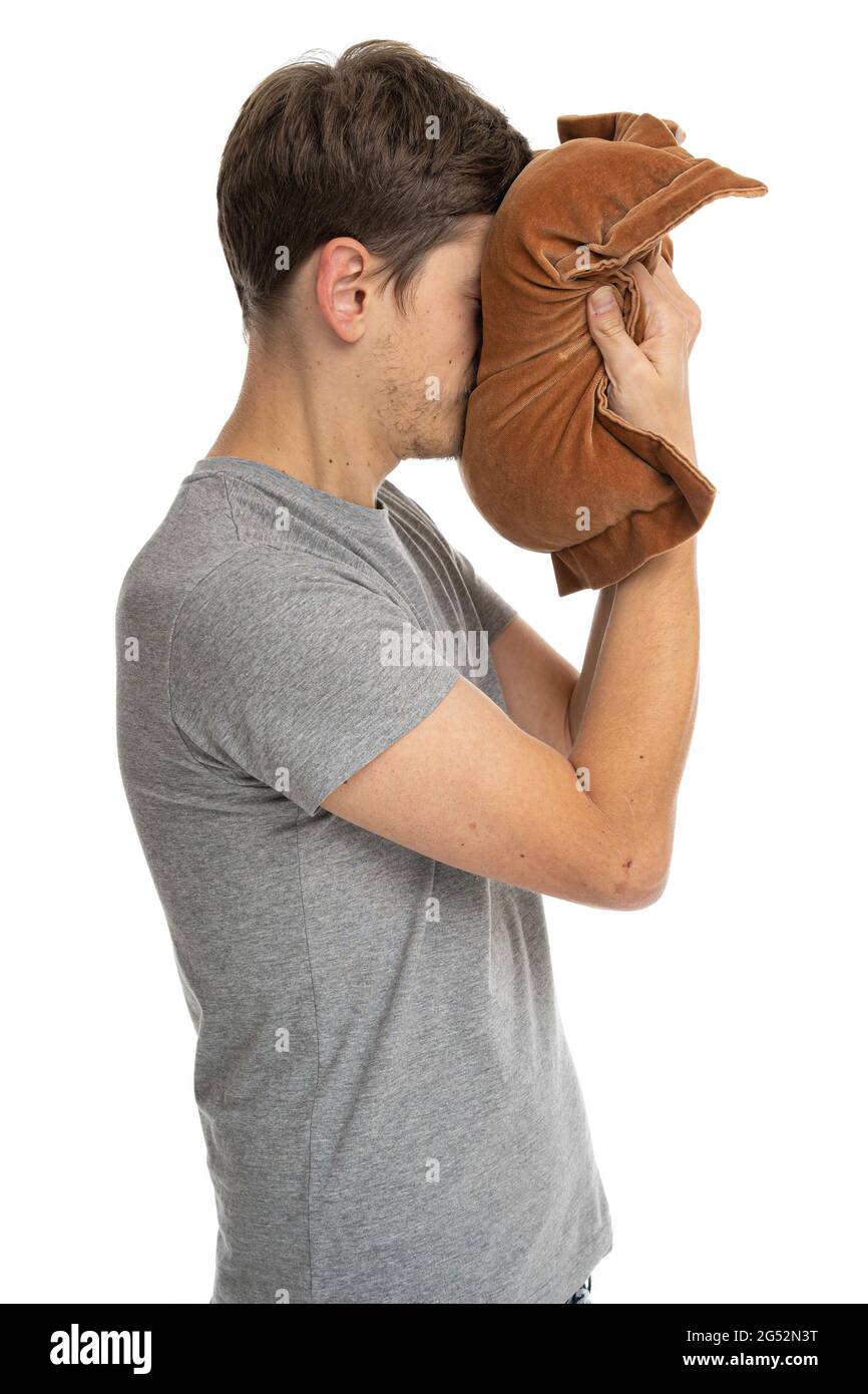 Young handsome tall slim white man with brown hair pushing brown pillow ...